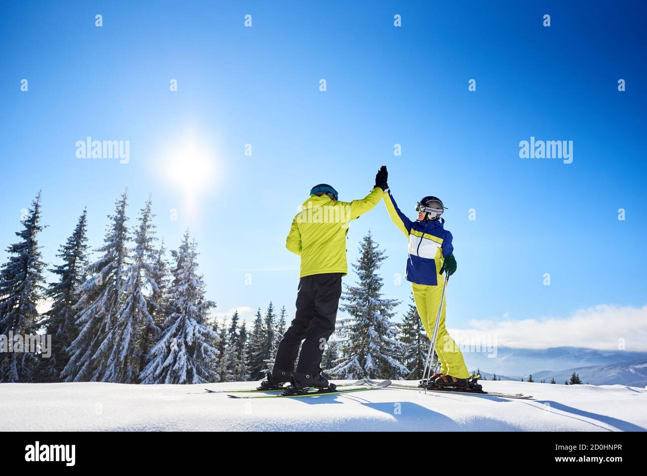 Couple high-five to each other under sunny blue sky high in mountains ...