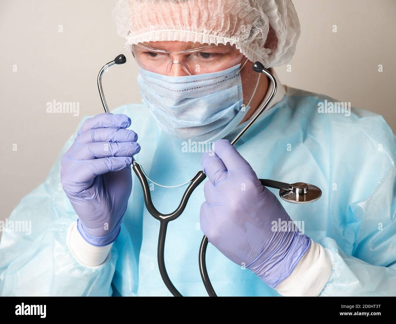 Doctor wearing protective gear gets ready to put his stethoscope to use ...