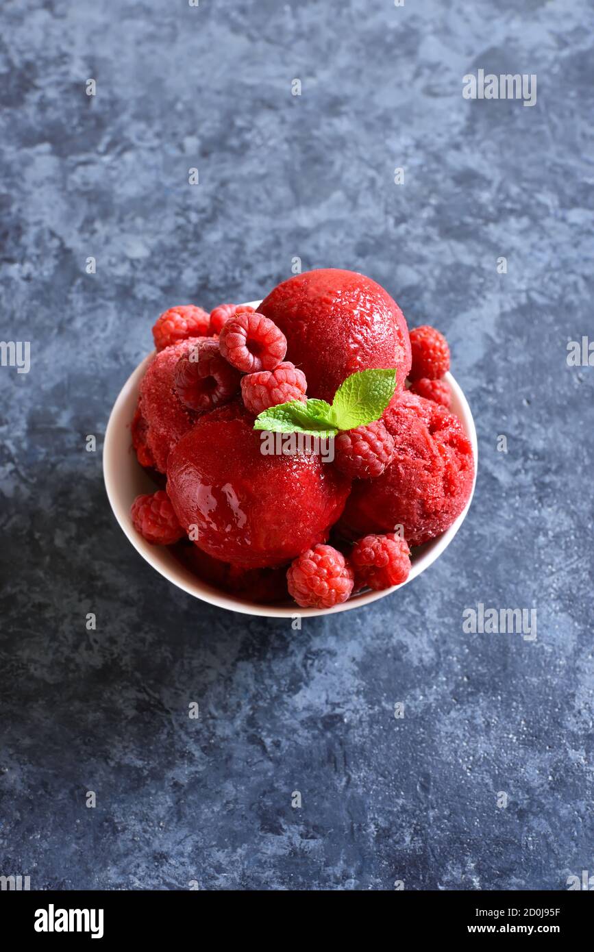 Raspberry Sorbet Ice Cream Scoop With Fresh Berries In Bowl Over Blue