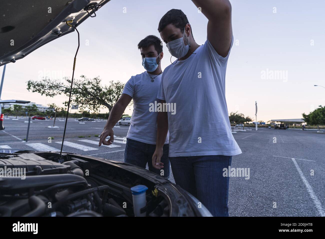Closeup shot of two male friends in masks repairing a car Stock Photo ...