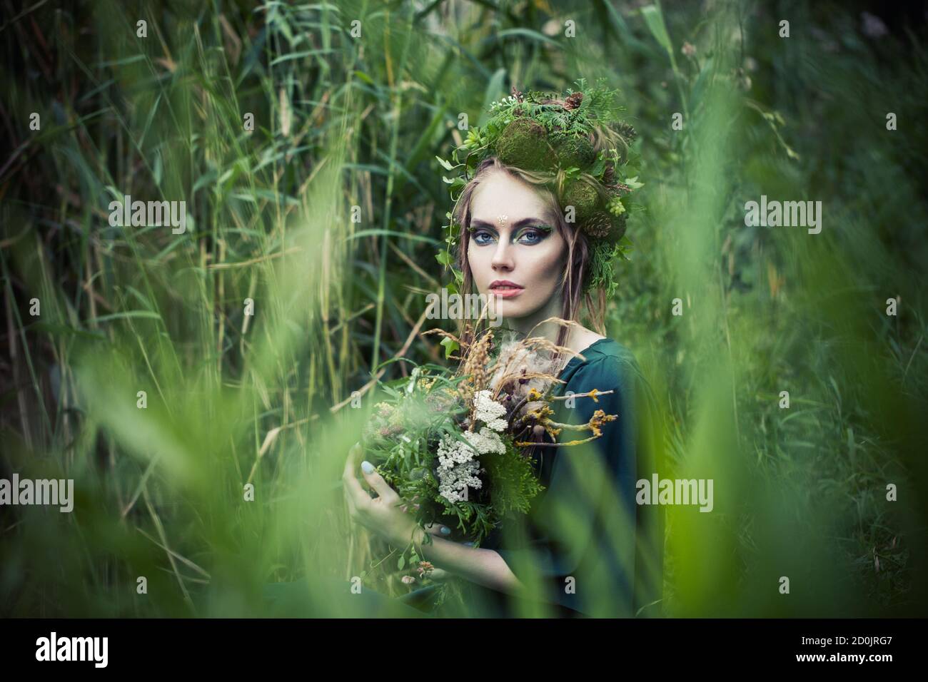 Beautiful fairy witch woman in green grass outdoors. Halloween ...