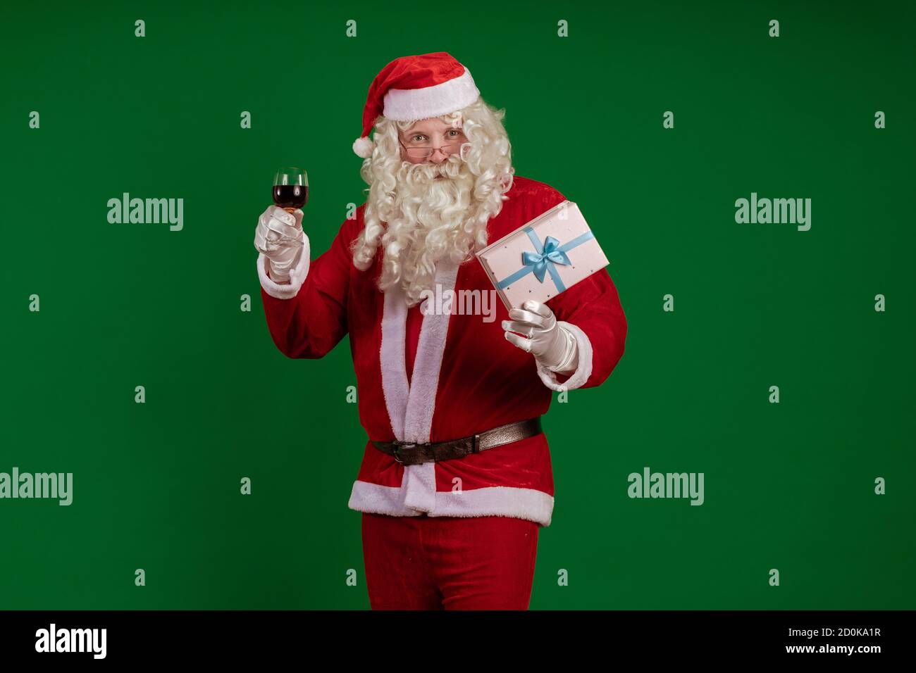 Emotional male actor in a costume of Santa Claus holds one gift box and ...