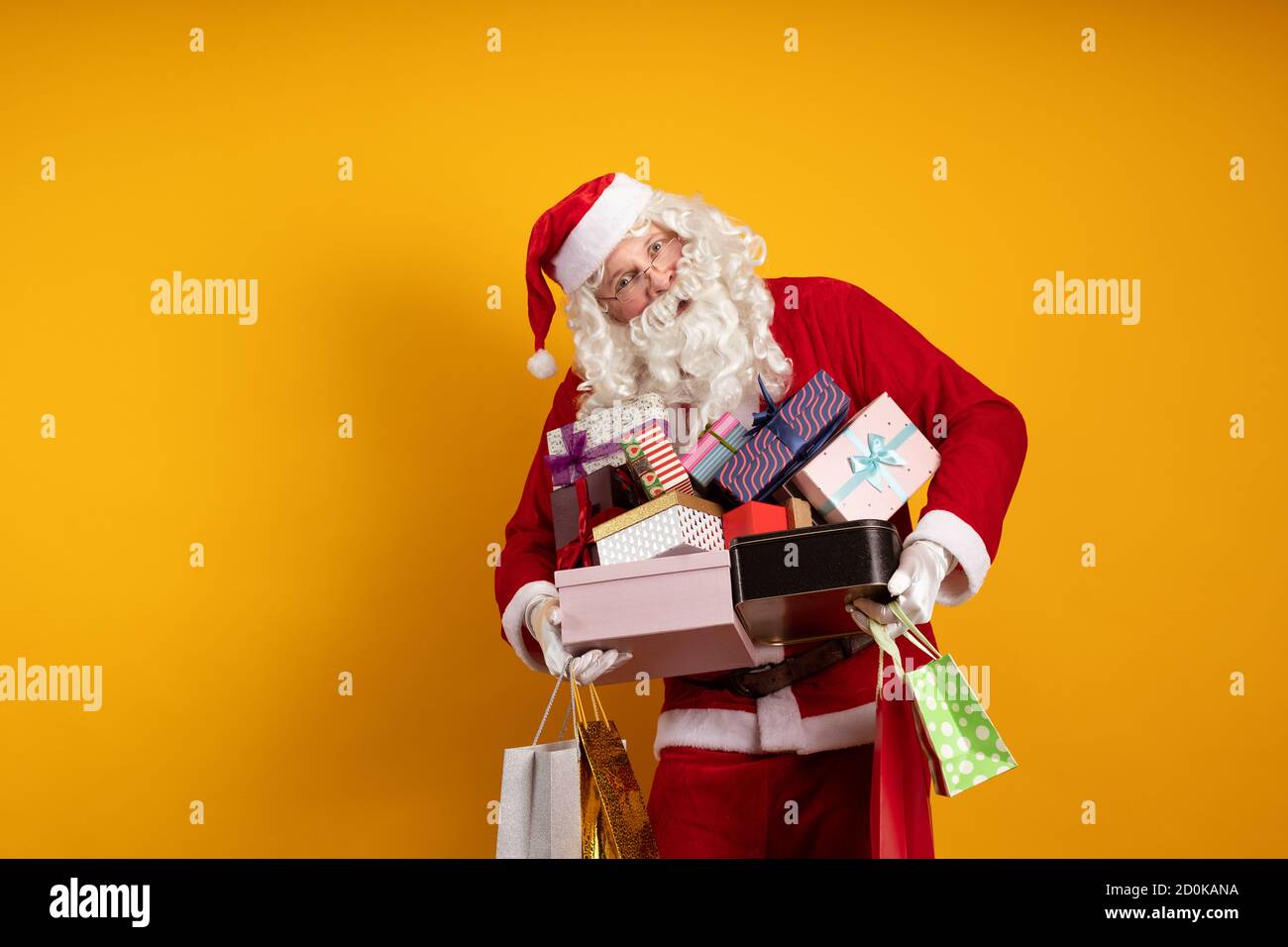 Santa Claus holds a lot of gift boxes and packages in his hands and ...