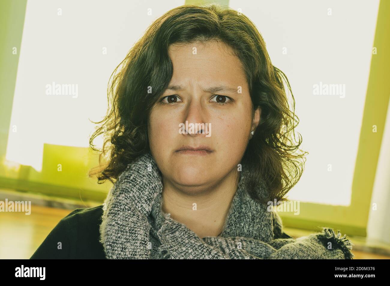 A young woman looks suspicious, insecure and a little fearful into the ...