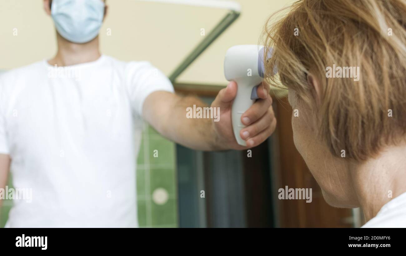 Measuring temperature on woman for coronavirus symptoms in a hospital ...