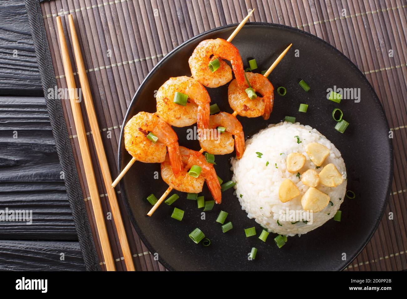 Delicious Japanese garlic fried rice served with shrimp kebabs close-up ...