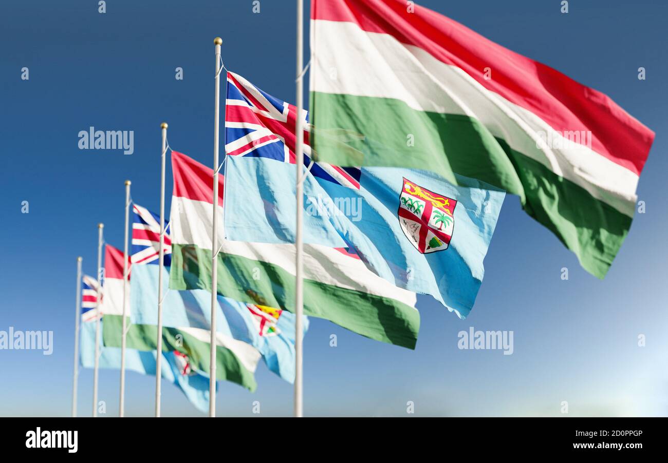 Hungary and Fiji flags waving at sky background. Concept of ...
