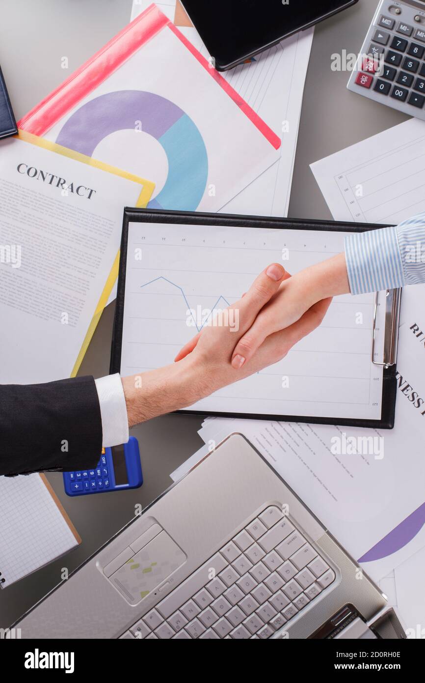 Business people shake hand over table with financial reports Stock ...