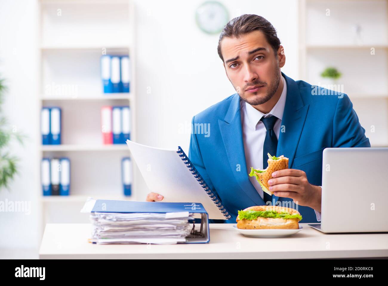 Young employee having breakfast at workplace Stock Photo - Alamy