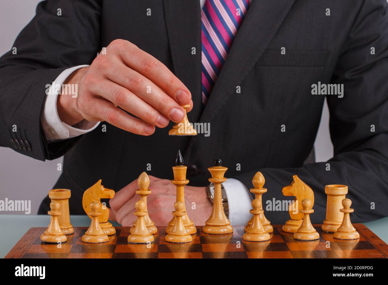 Businessman hand holding a chess piece over chessboard Stock Photo - Alamy