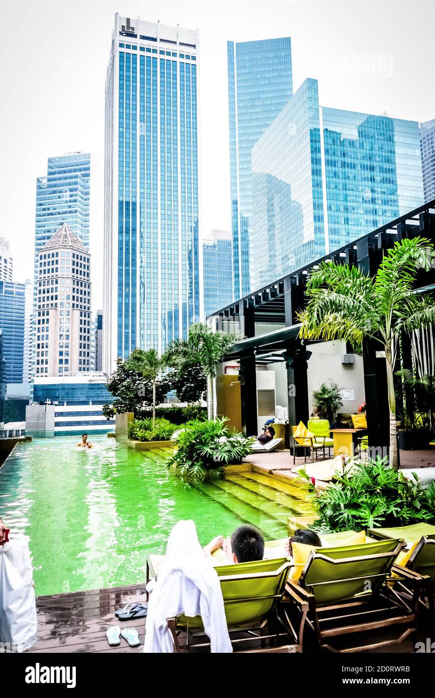 Rooftop swimming pool in city with suntanning deck chairs and sun ...