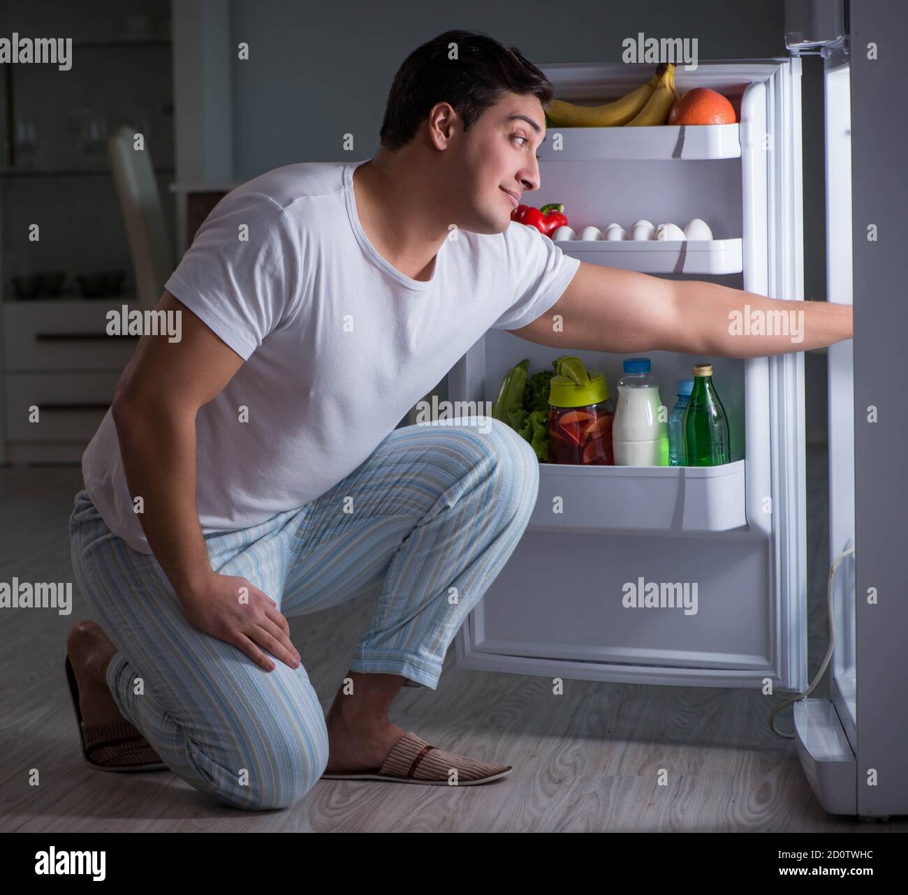 Man at the fridge eating at night Stock Photo - Alamy