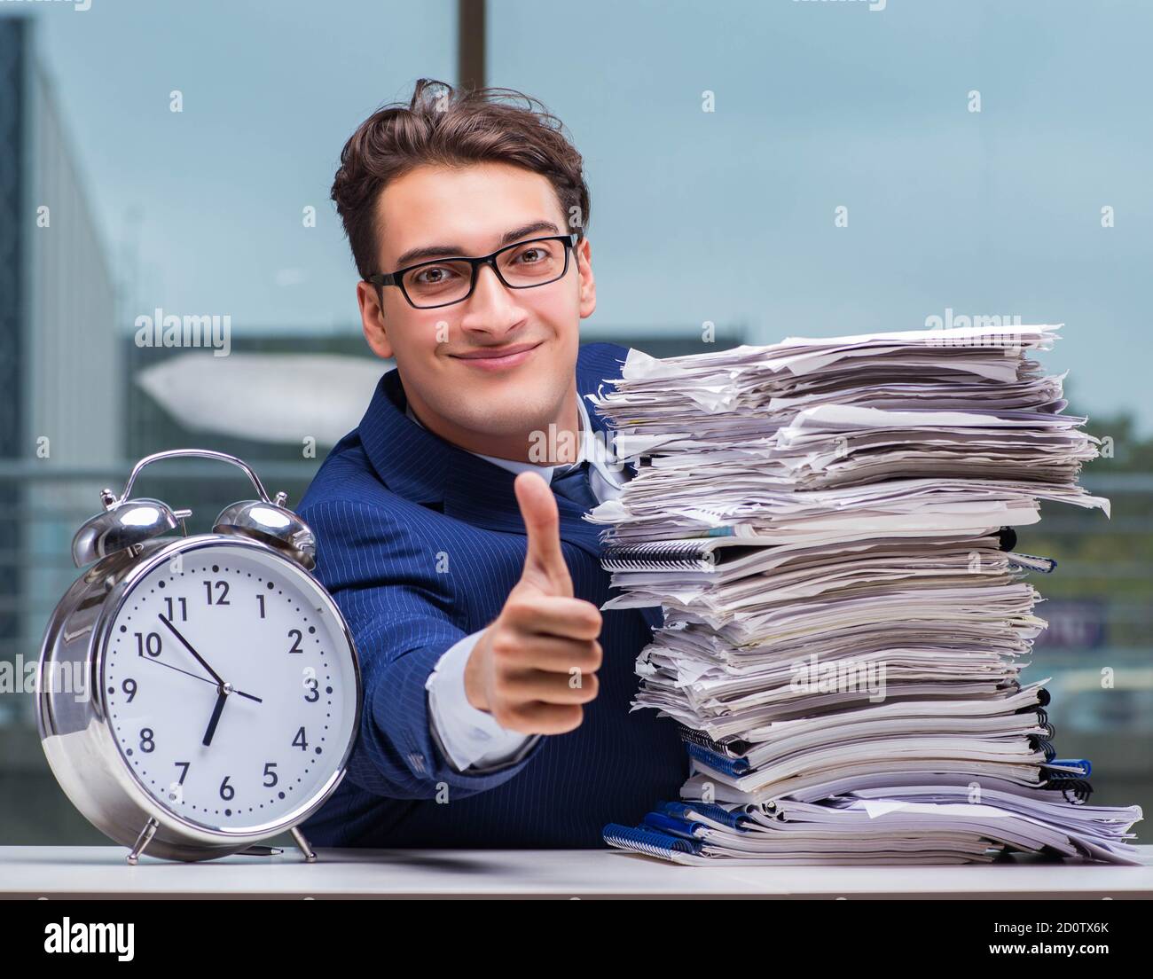 Businessman with pile stack of paper paperwork and an alarm clock ...