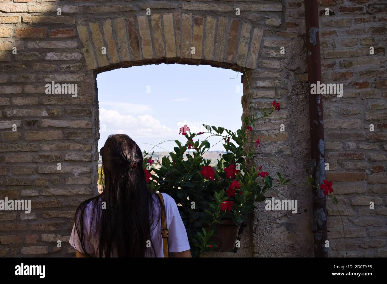A brunette woman is looking outside the window of a medieval village ...
