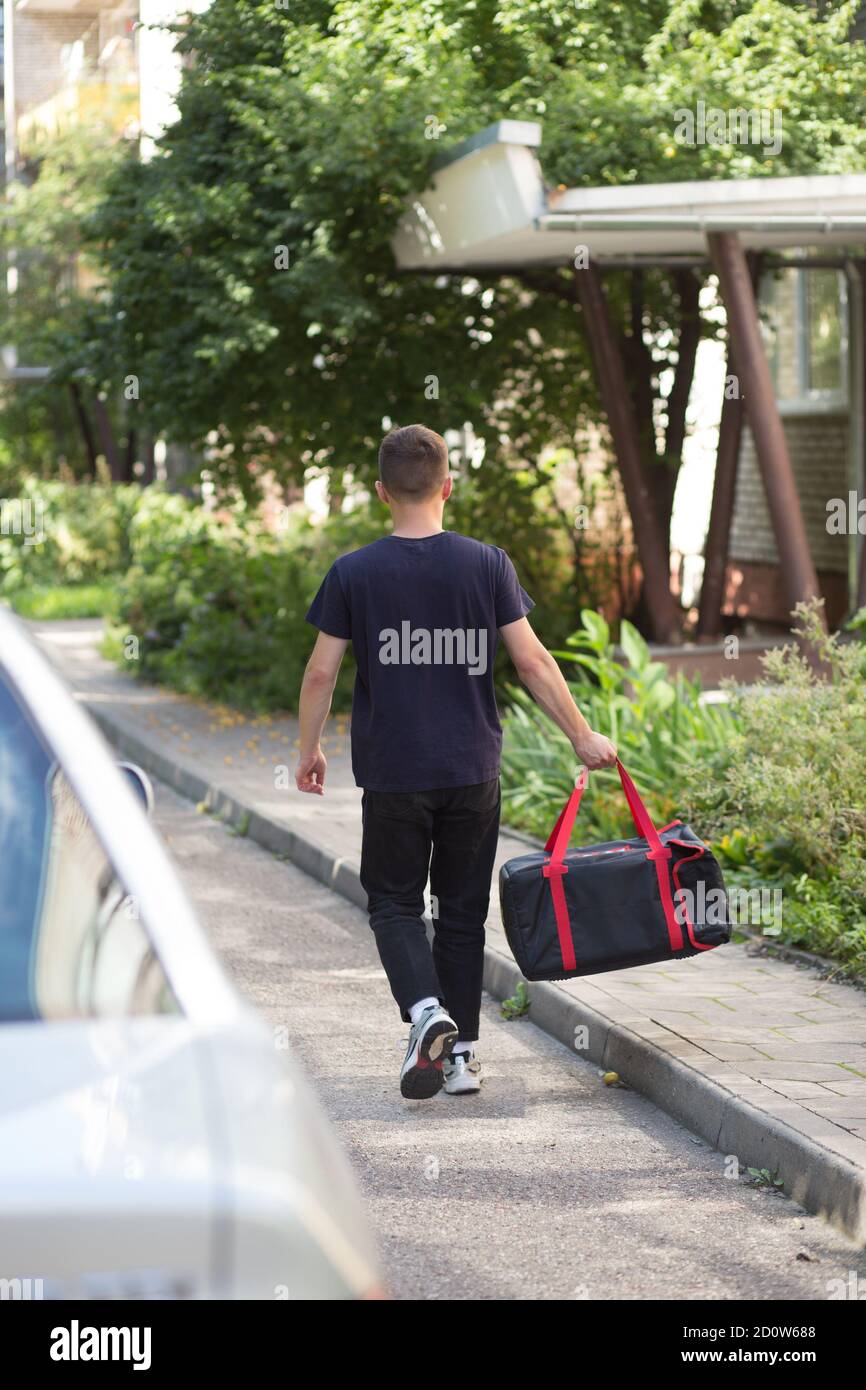 Young deliveryboy walking with night thermal bag on city street. Man of ...