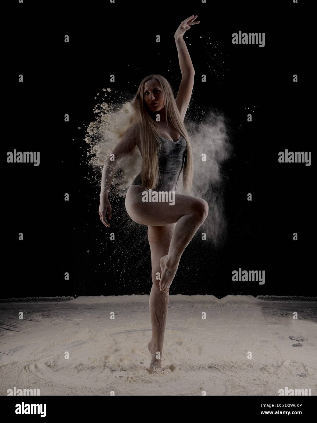 Beautiful sensual fit slim dancer in black body with long blond hair throwing dust, flour ...