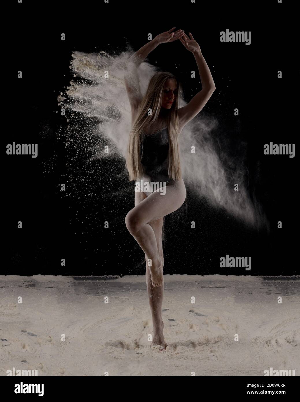 Beautiful sensual fit slim dancer in black body with long blond hair throwing dust, flour ...