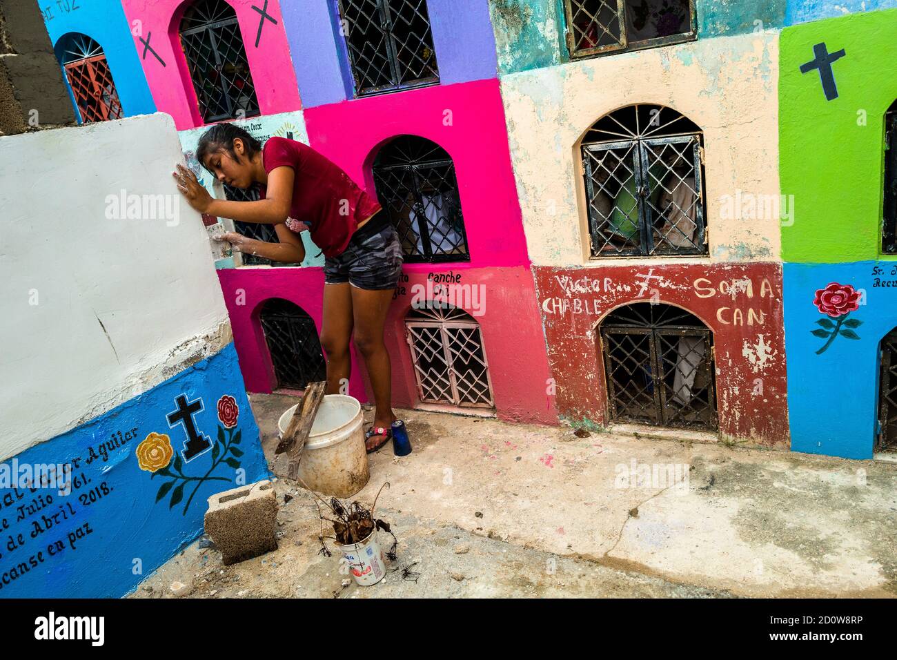A Mayan girl repairs parging of a niche during the bone cleansing ...