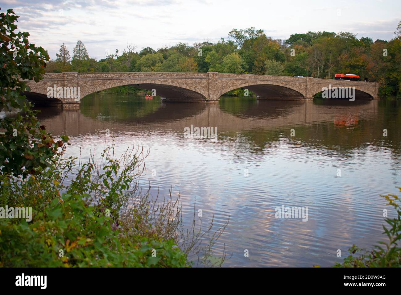 Reflections of a roadway bridge, vegetation, and cloudy skies at the ...