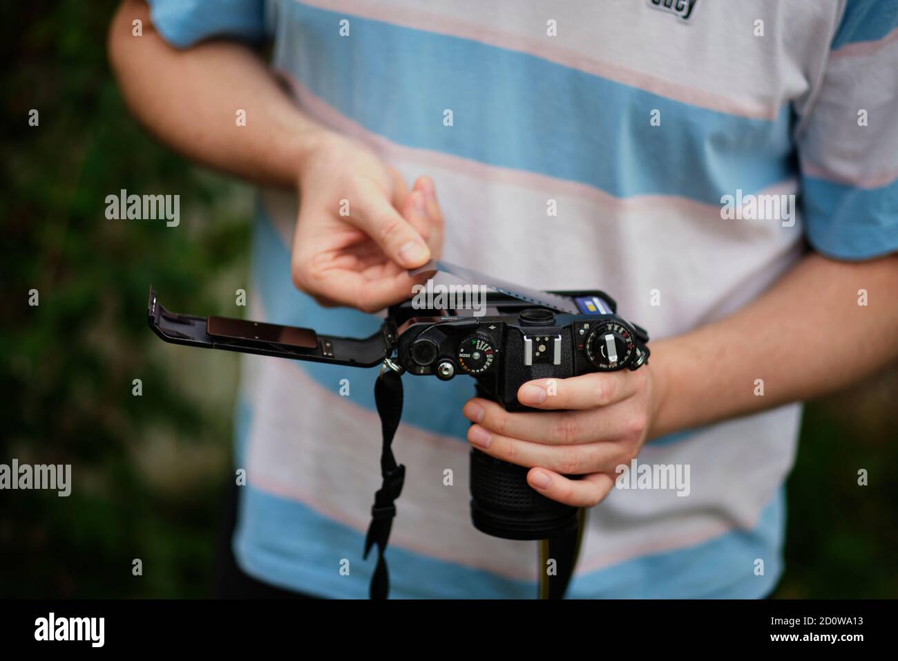 A young man loads photographic film into an analogue camera, a medium ...