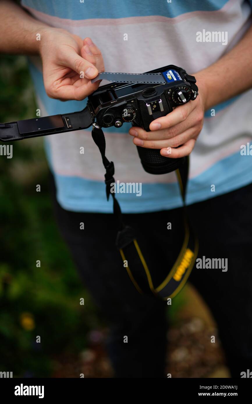A young man loads photographic film into an analogue camera, a medium ...
