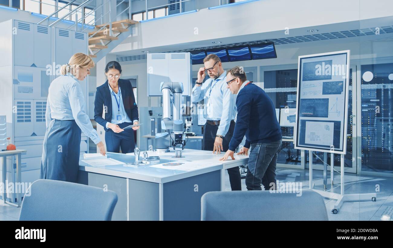 Diverse Team of Industrial Robotics Engineers Gathered Around Table ...