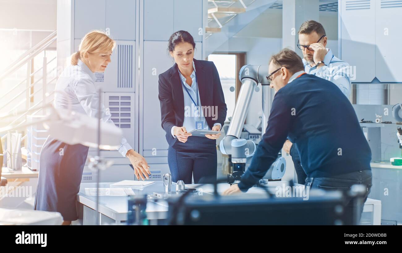 Diverse Team of Industrial Robotics Engineers Gathered Around Table ...