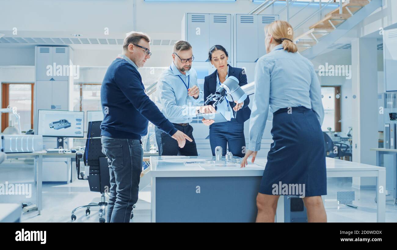 Diverse Team of Industrial Robotics Engineers Gathered Around Table ...
