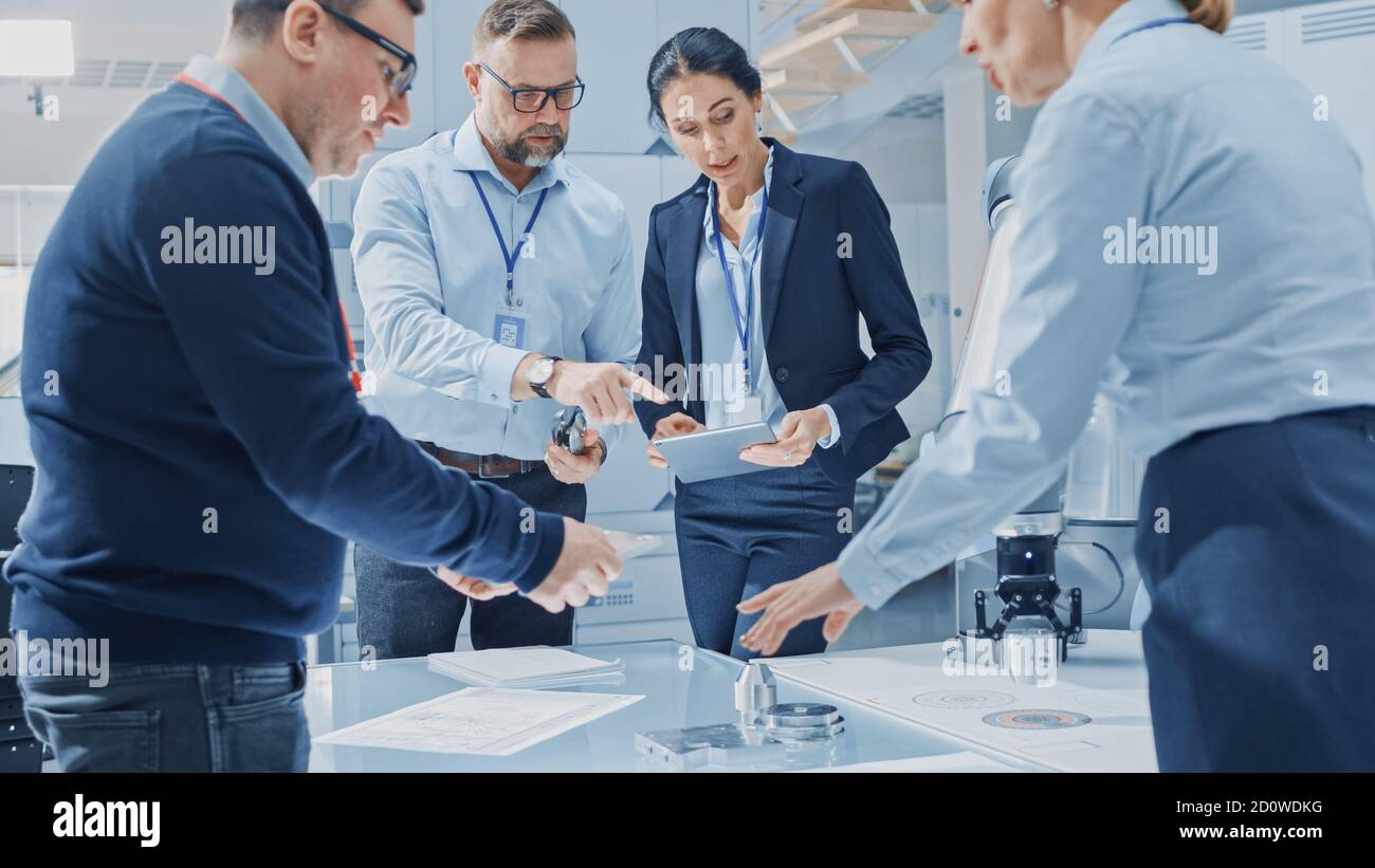 Diverse Team of Industrial Robotics Engineers Gathered Around Table ...