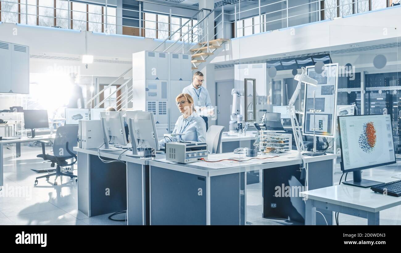 Senior Female Chef Engineer Working on Computer, Programming Robot Arm in Bright Modern ...