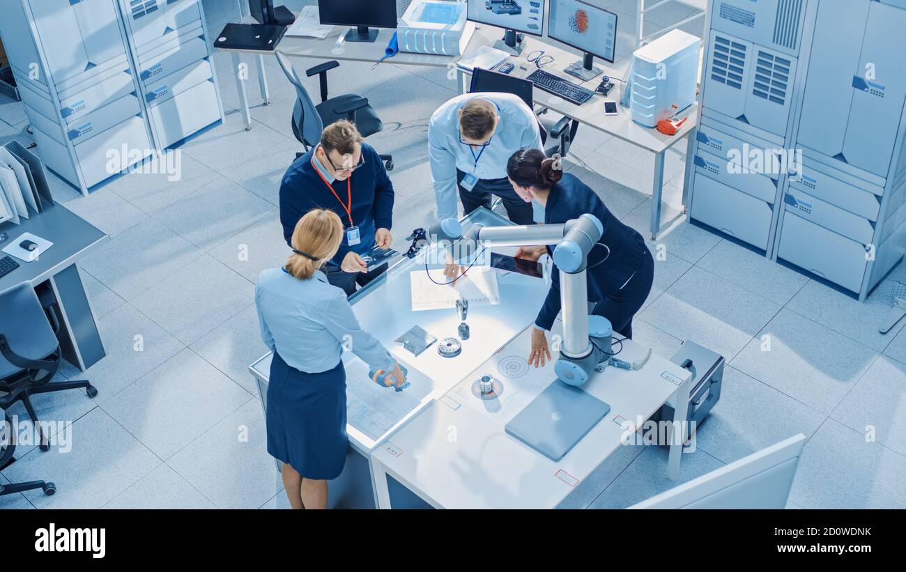 Team of Industrial Robotics Engineers Gathered Around Table With Robot ...
