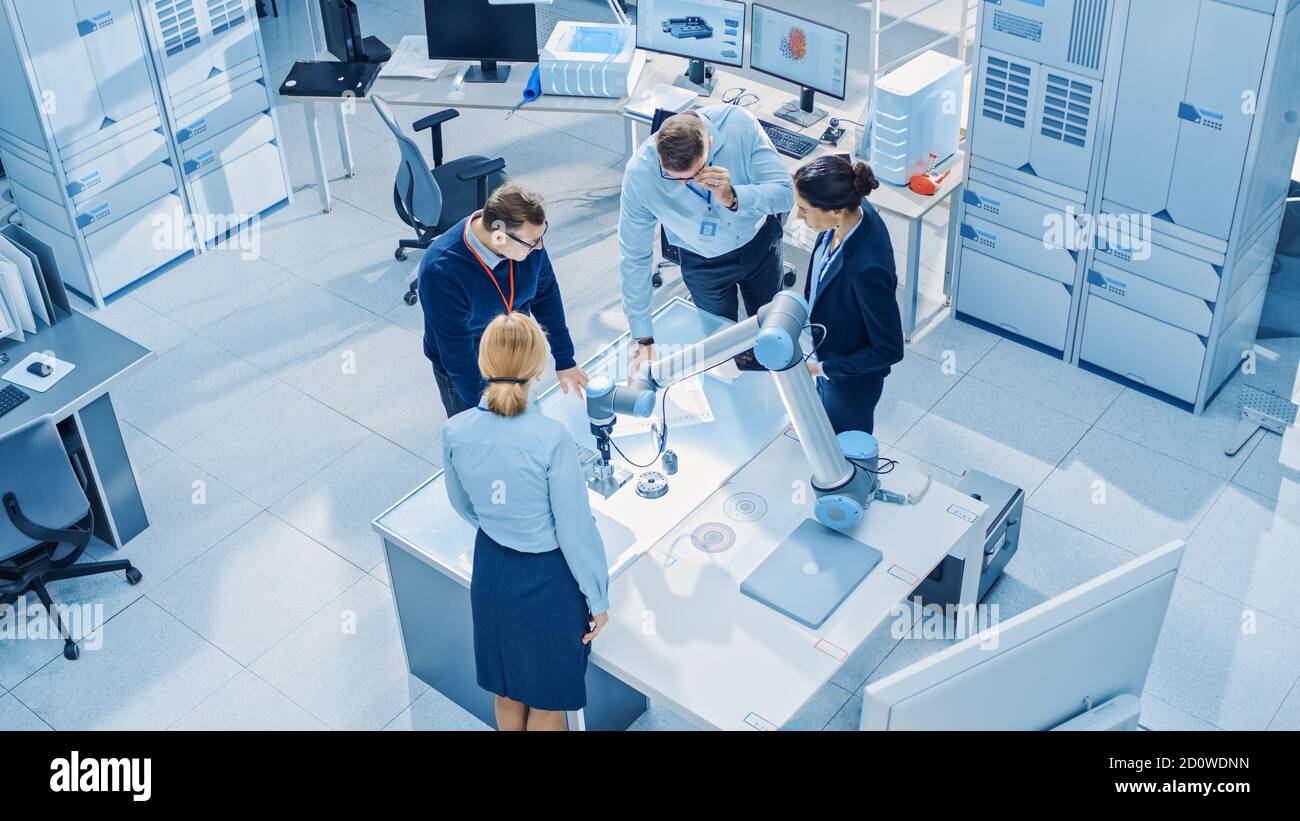 Team of Industrial Robotics Engineers Gathered Around Table With Robot ...