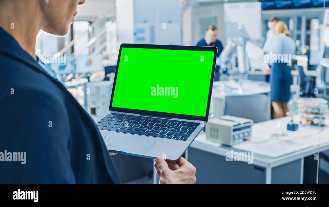 Engineer Holds Green Mock-up Screen Laptop Computer. In the Background ...