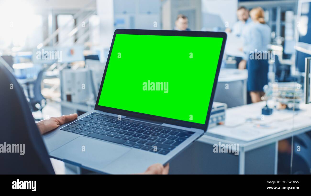 Engineer Holds Green Mock-up Screen Laptop Computer. In the Background ...