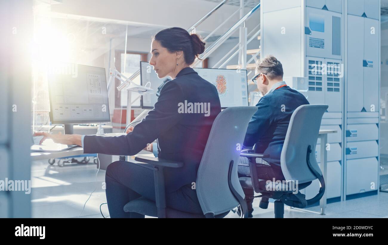Back View of Team of Technology Engineers Working on Desktop Computers in Bright Office. Screens ...