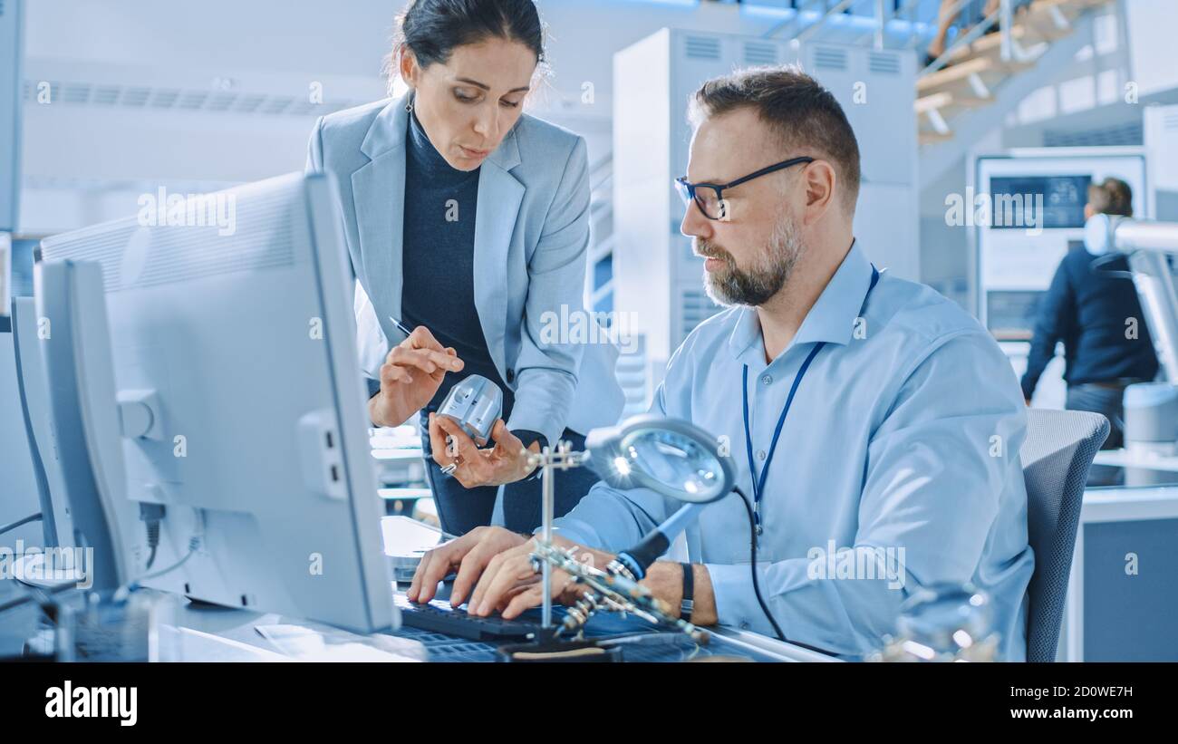 Female Industrial Engineer Talks with Electronics Specialist, She Holds ...