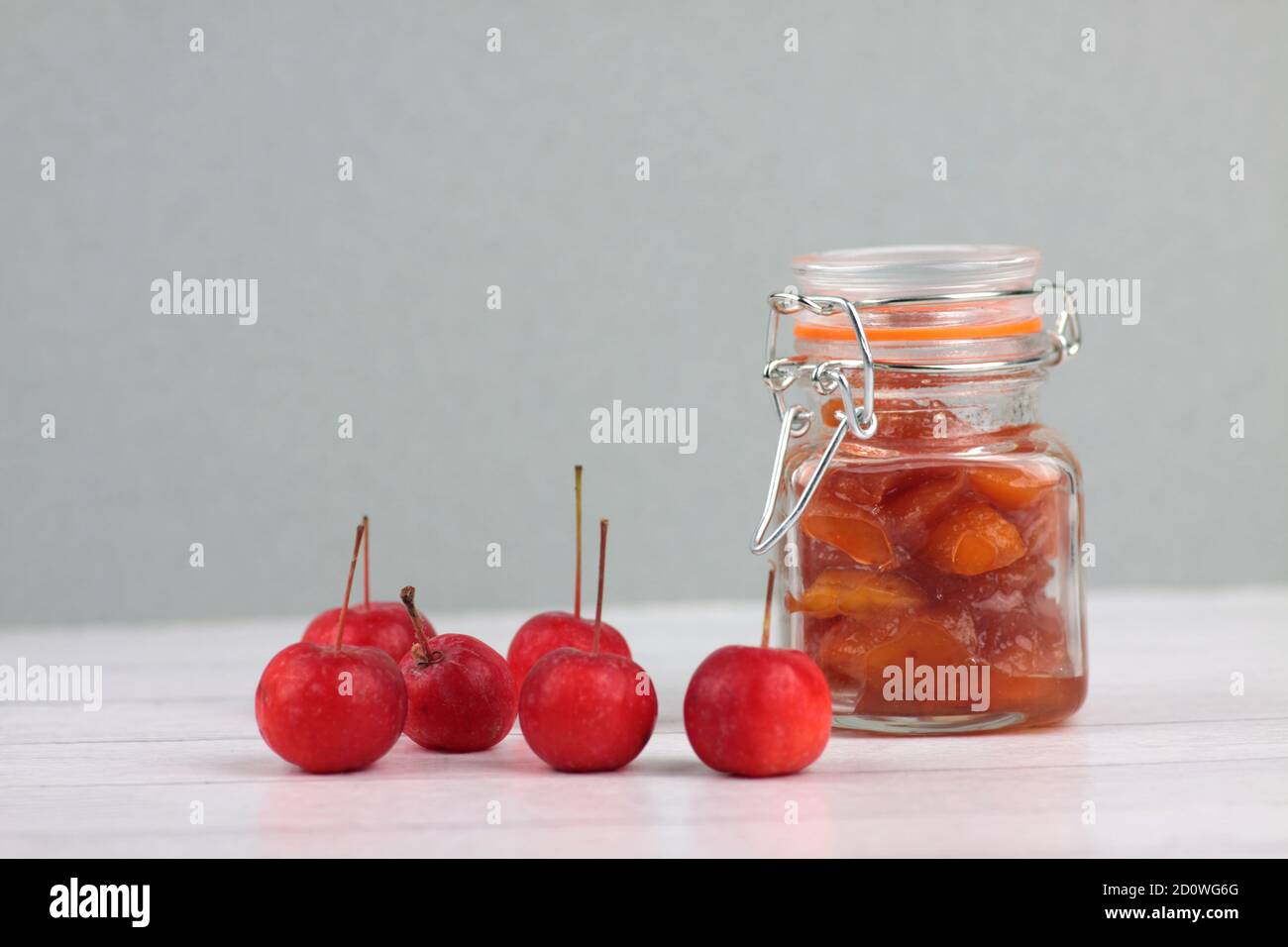 glass can of apple jam and red apples on white wooden background. Image ...