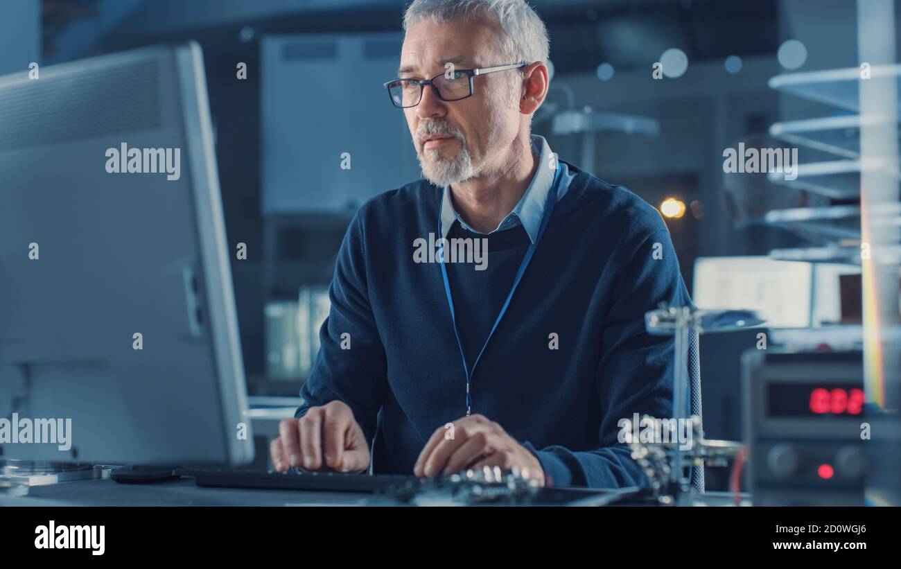 Middle Aged Electronics Repair Engineer Working on Personal Computer in ...