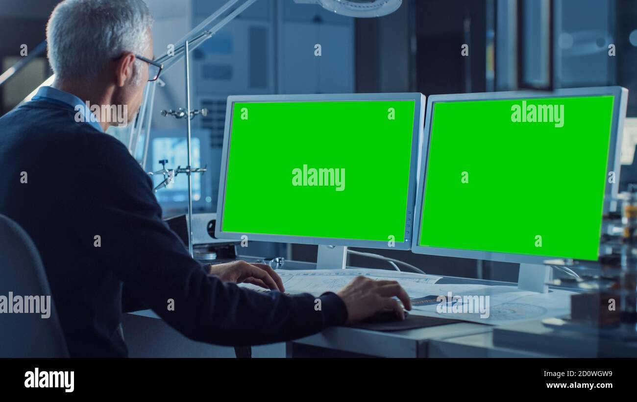 Professional Engineer Works on Computer with Two Green Mock-up Screen ...