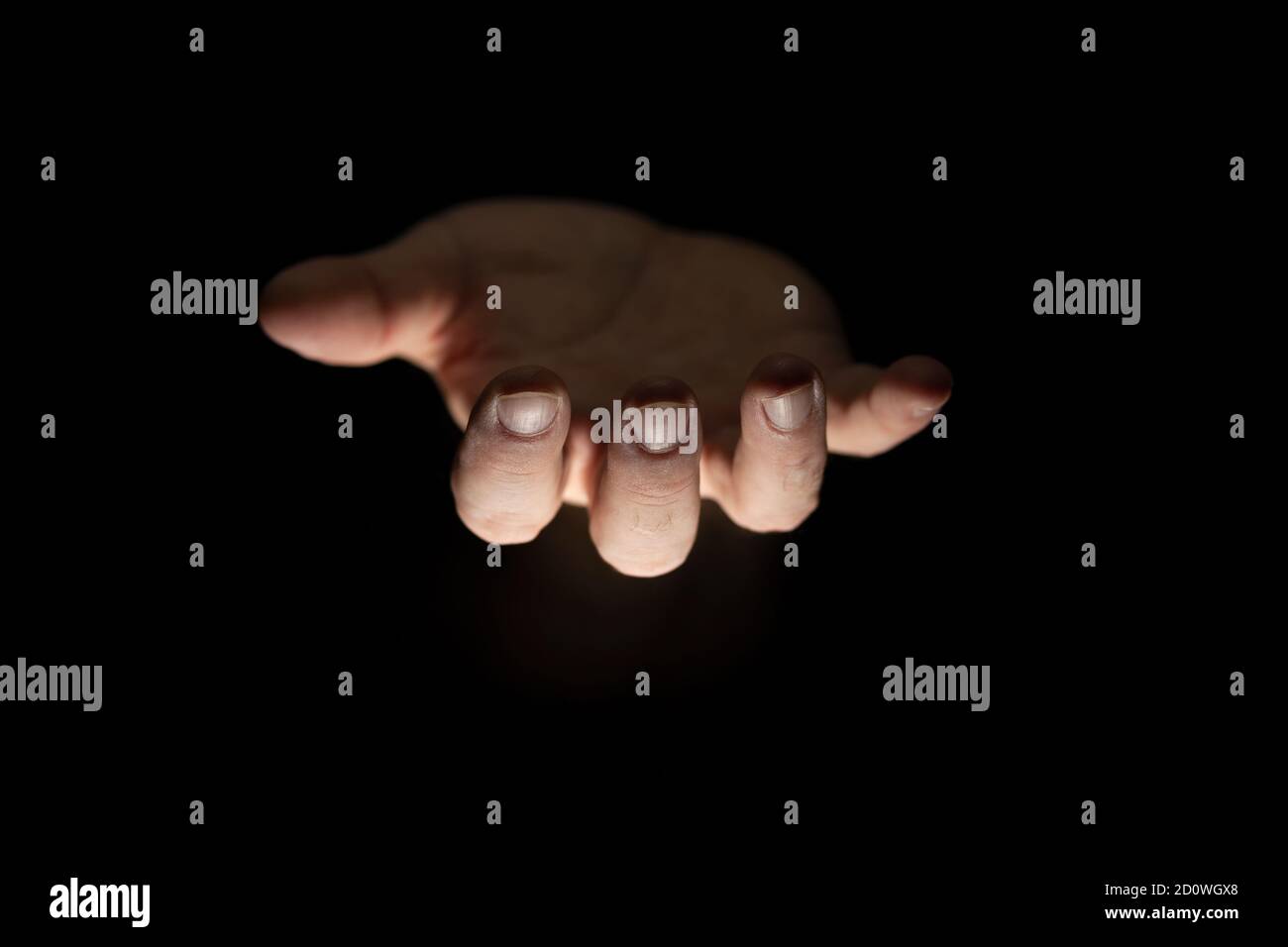 Male hand in the dark, palms facing upward, illuminated from below ...