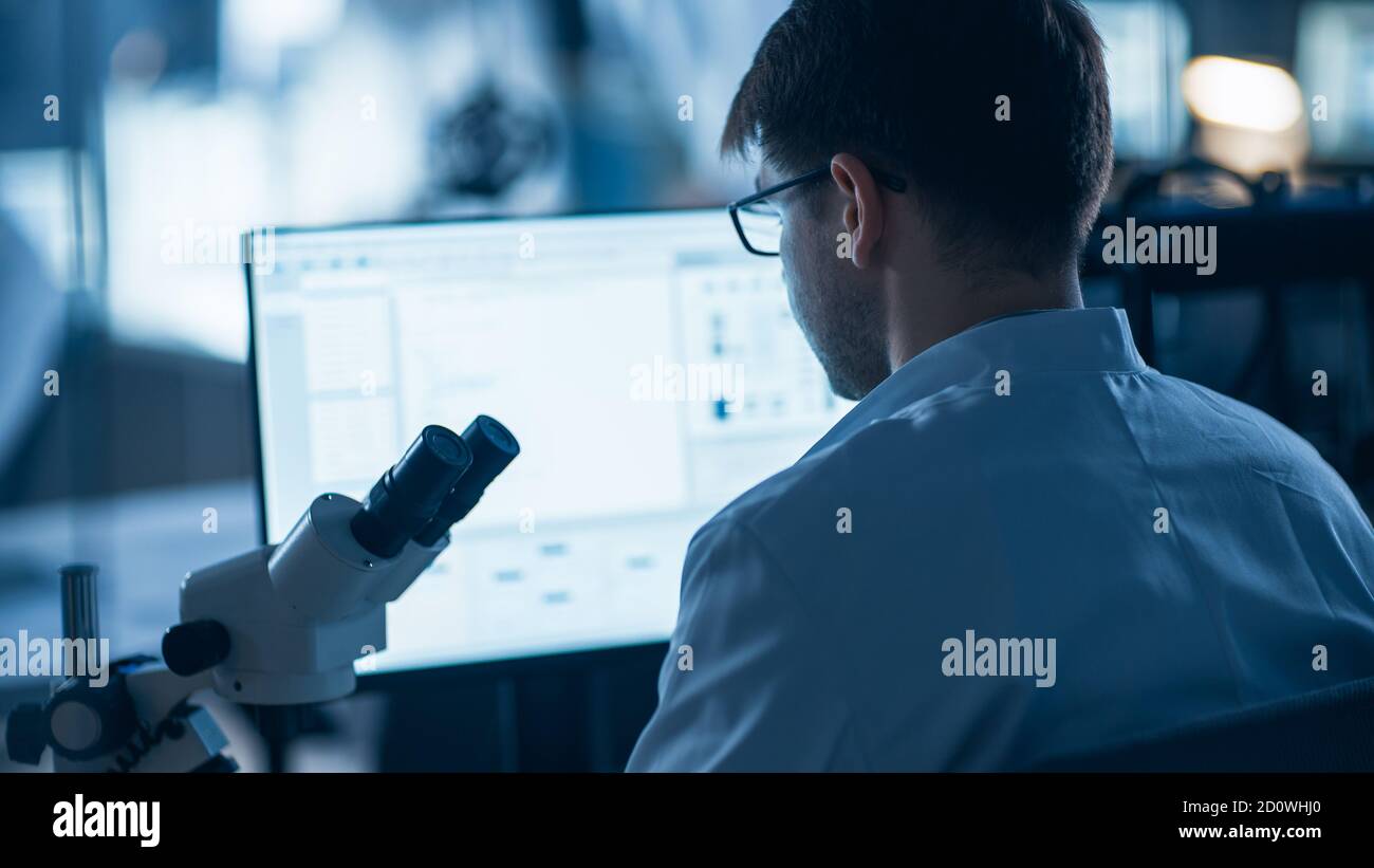 Shot of a Male IT Scientist Uses Computer with Electronic Microscope ...