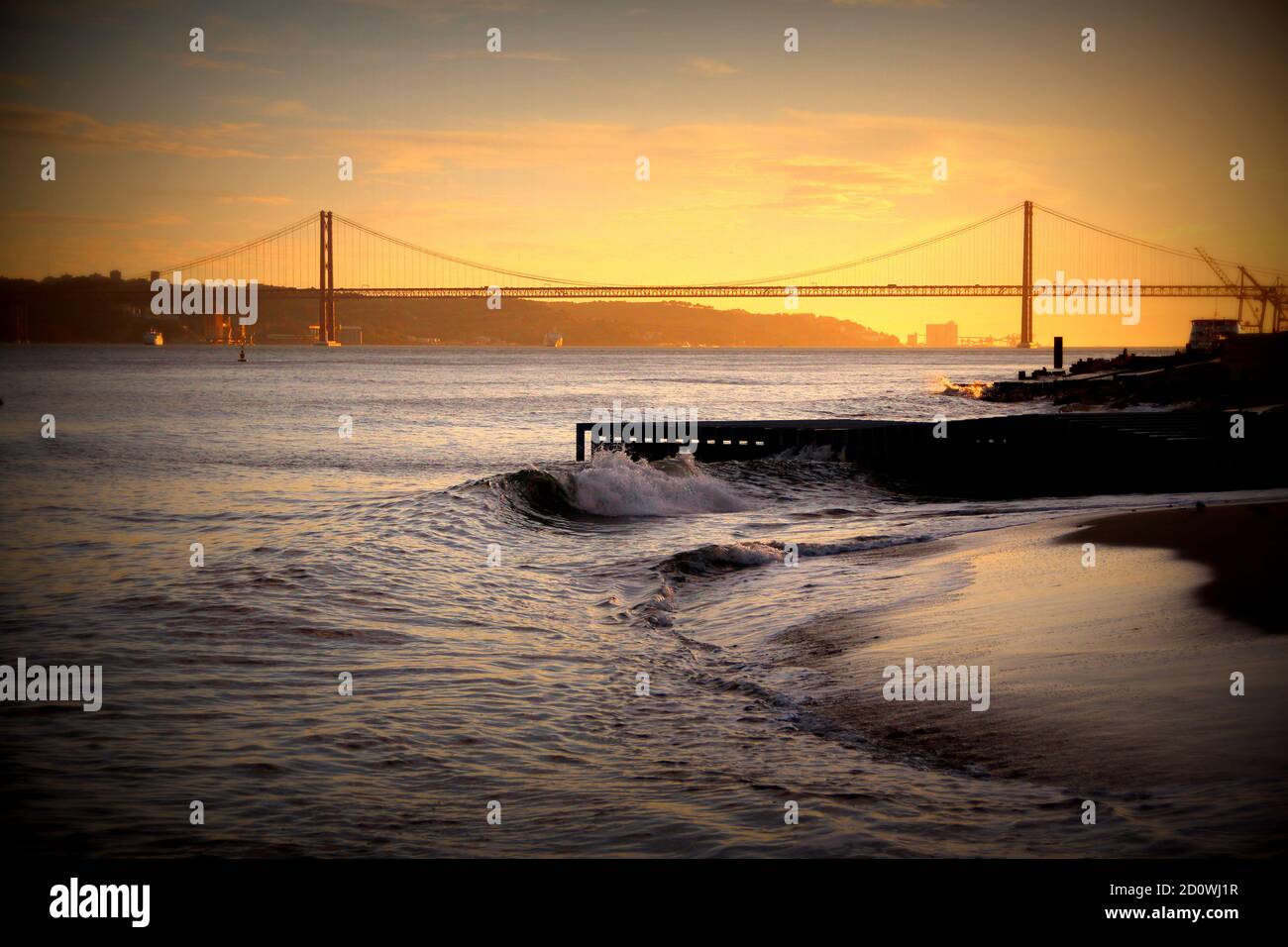 Orange sky and sun at the beach with water rolling over the sand Stock ...
