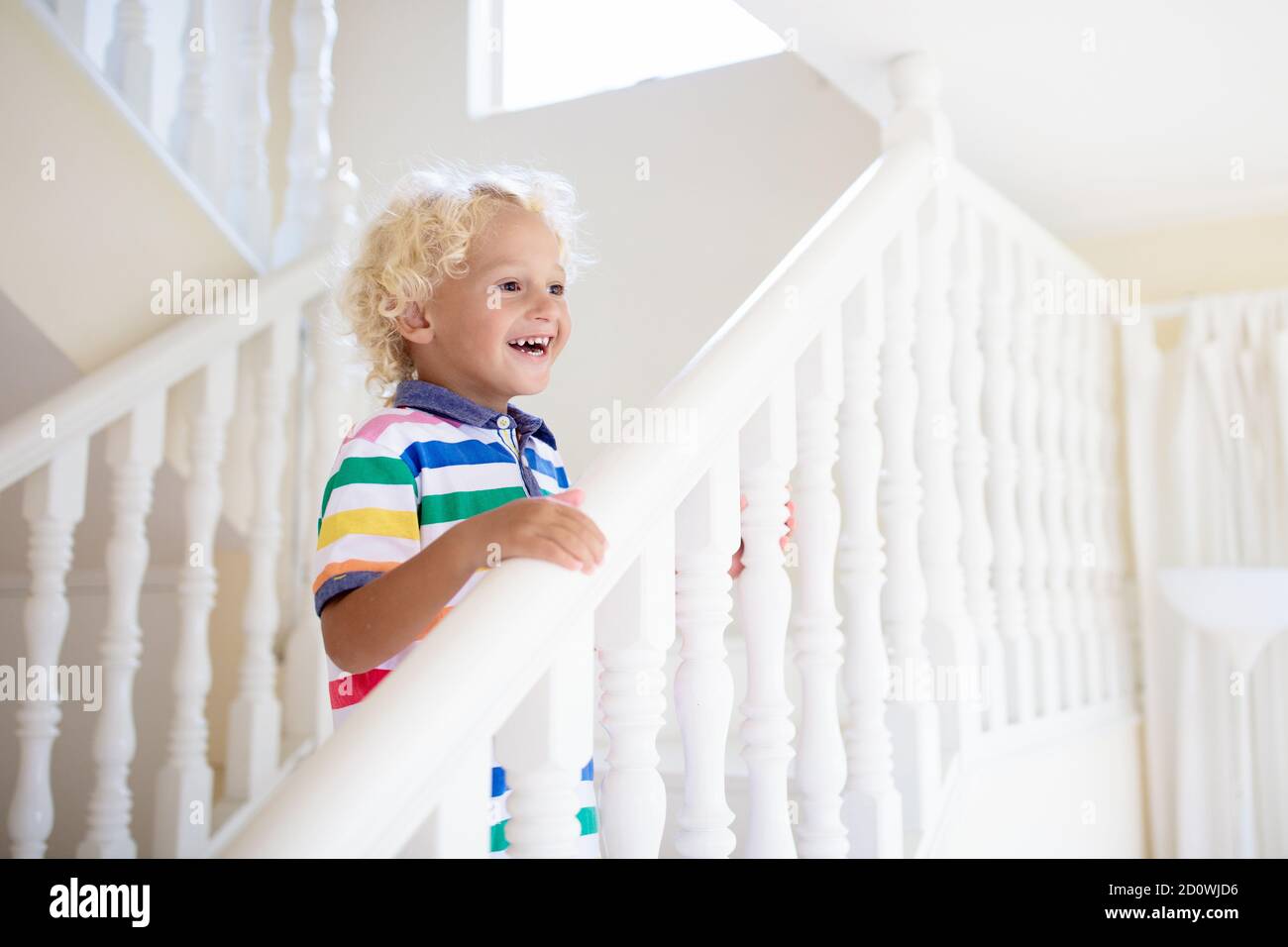Kid walking stairs in white house. Little boy playing in sunny ...