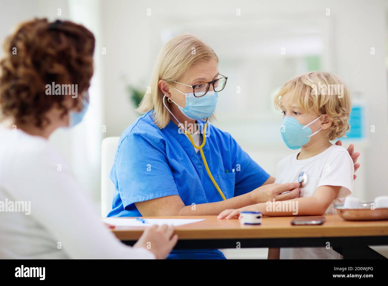 Pediatrician doctor examining sick child in face mask. Ill boy in ...