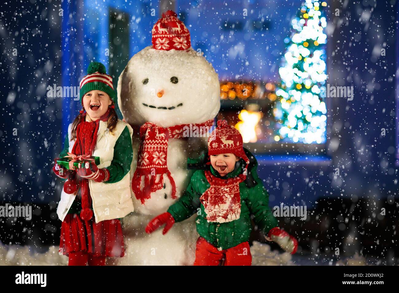 Kids build snowman on Christmas eve. Children in snowy backyard next to ...