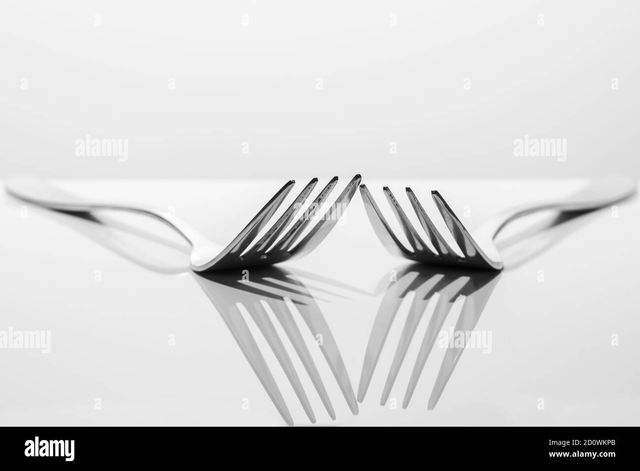 Two forks with reflections on light background, closeup with selective ...