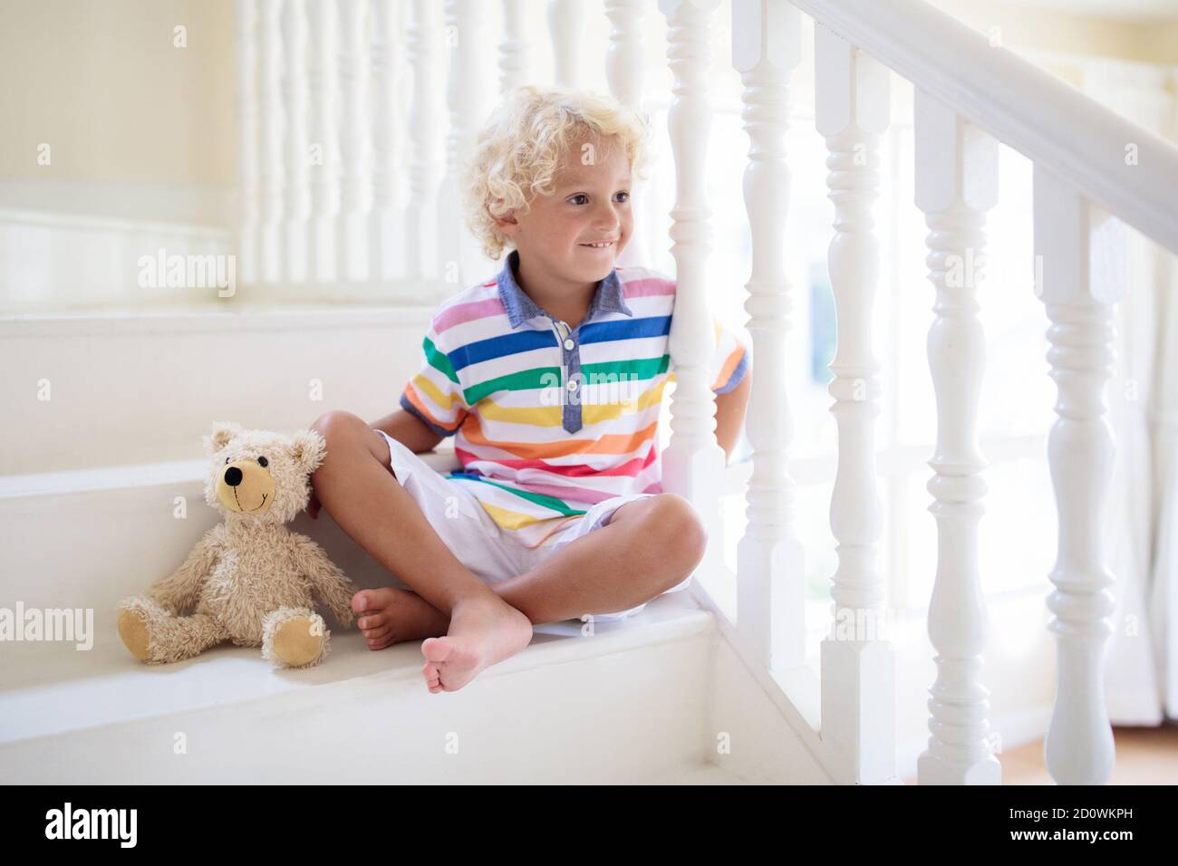 Kid walking stairs in white house. Little boy playing in sunny ...