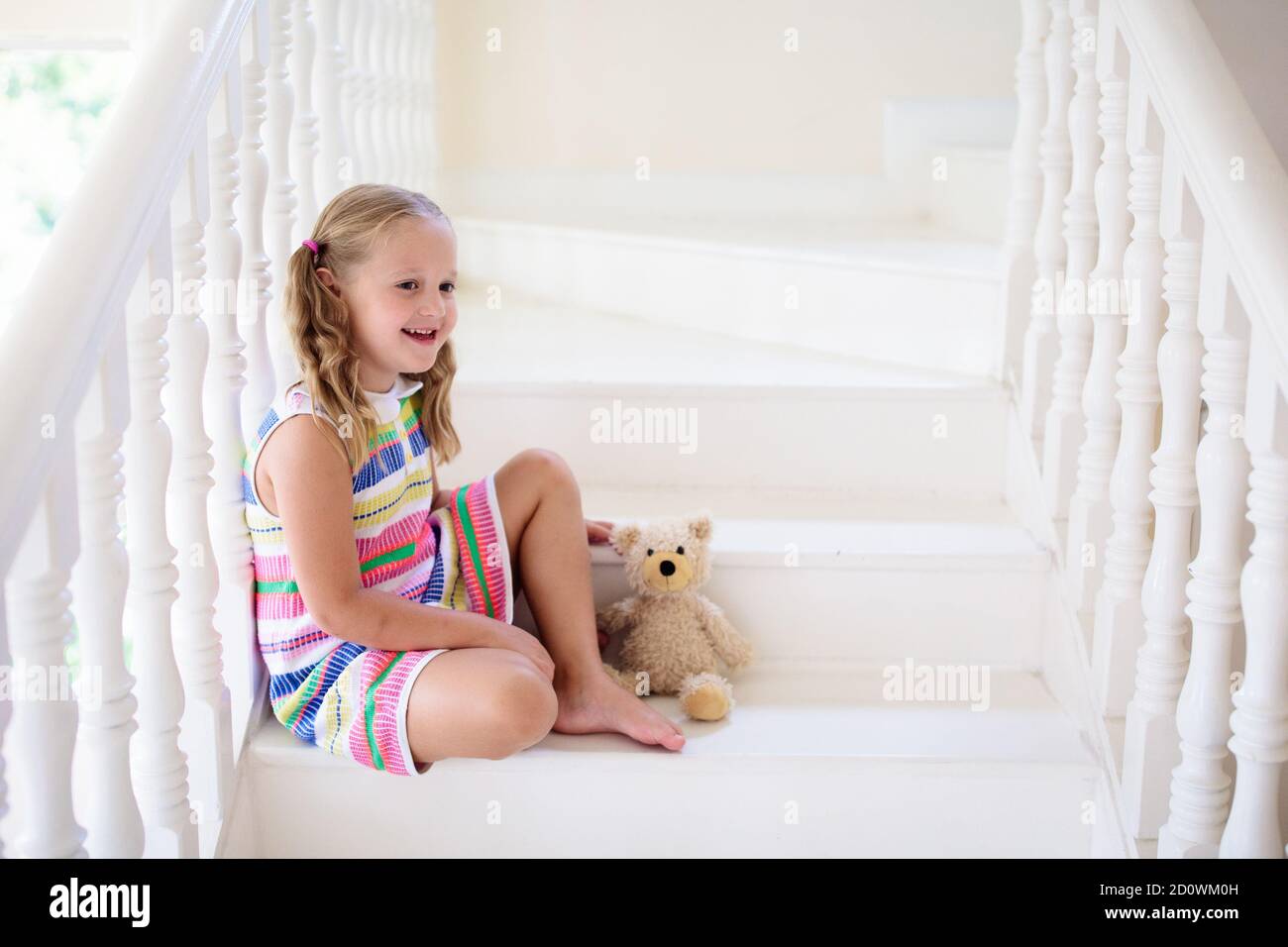 Kid walking stairs in white house. Little girl playing in sunny ...