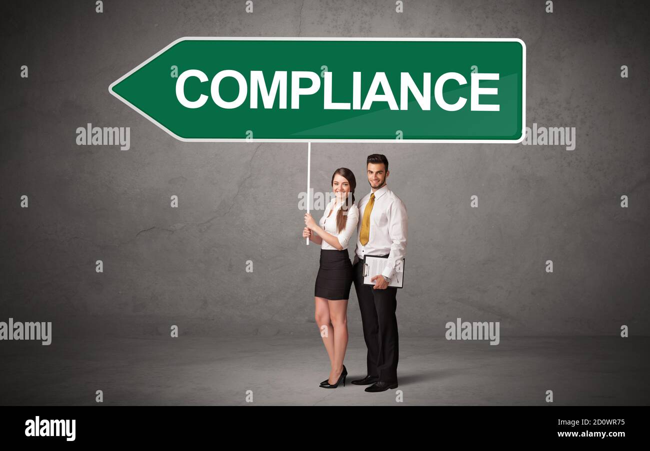 Young business person in casual holding road sign with COMPLIANCE ...