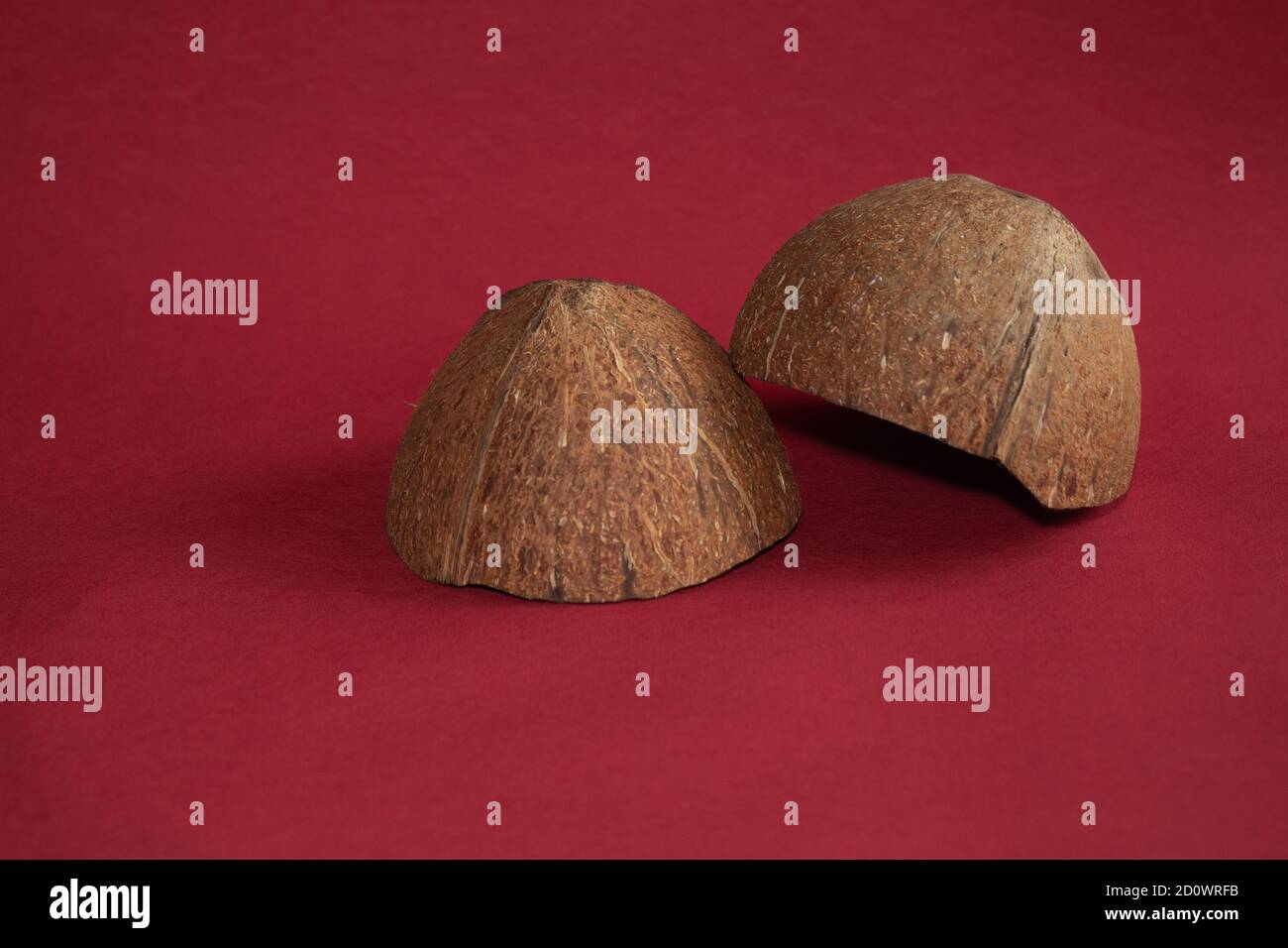 Coconut fruit shells cut in half and insulated on a smooth red ...